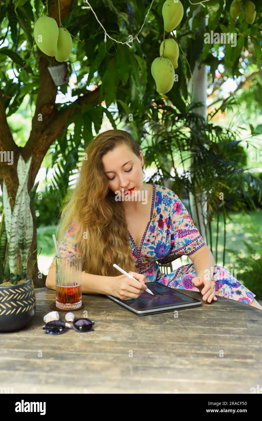 Beautiful blonde woman artist and illustrator drawing, sitting by the ...