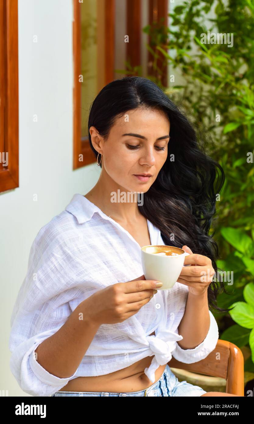 Portrait of smiling ukrainian woman drinking hot capuccino and looking ...