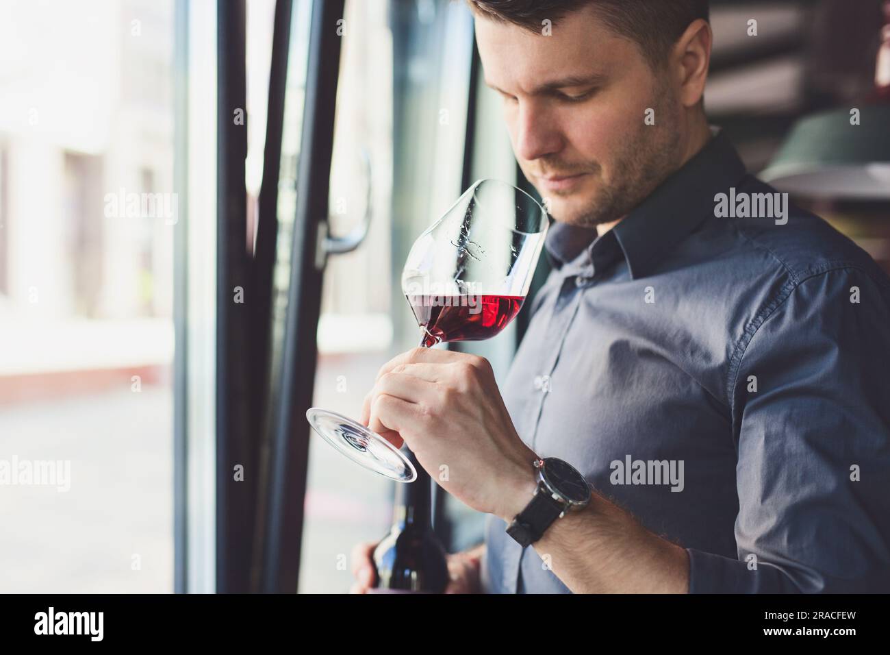 Handsome guy standing near open window with wine Stock Photo - Alamy