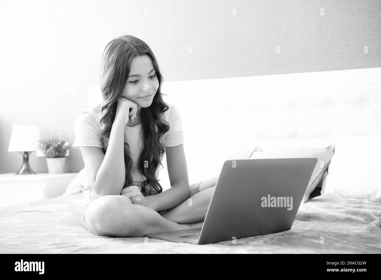 Teenager child girl browsing internet in a laptop in the bedroom at ...