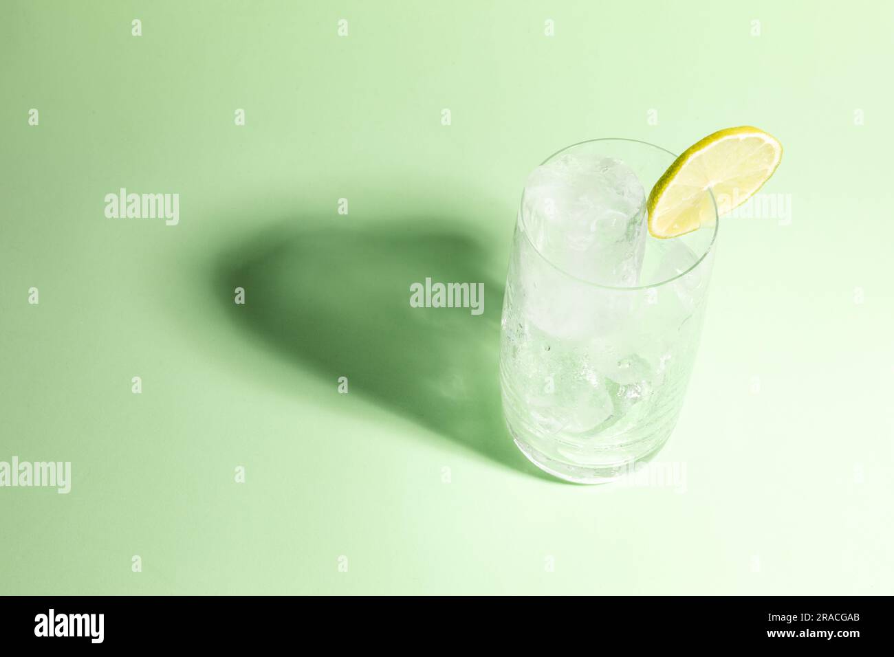 Cold glass full of ice with a lime, ready to serve light green with ...