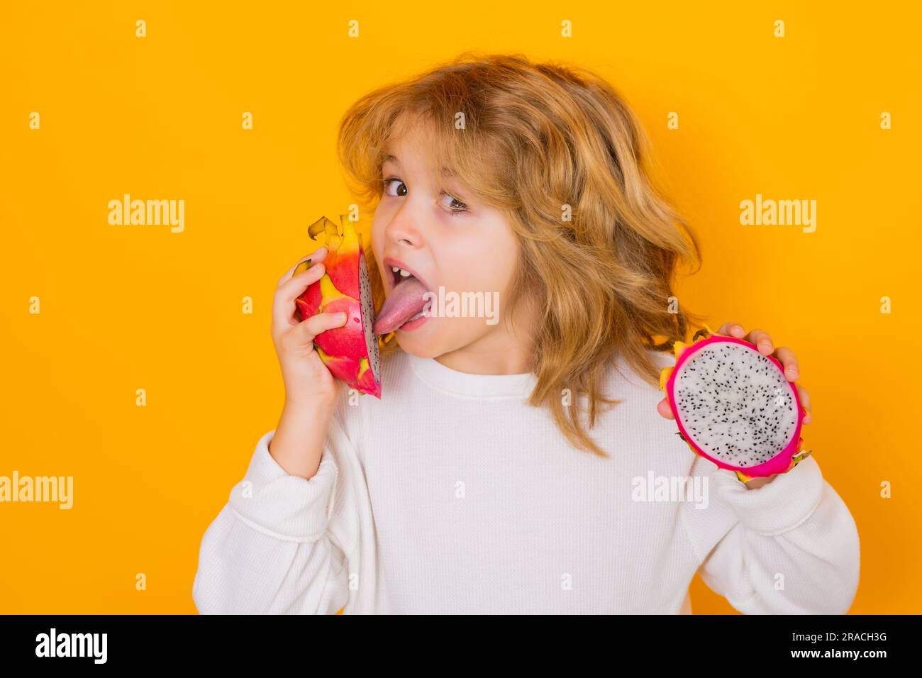 Kid eat dragon fruit in studio. Studio portrait of cute child with ...