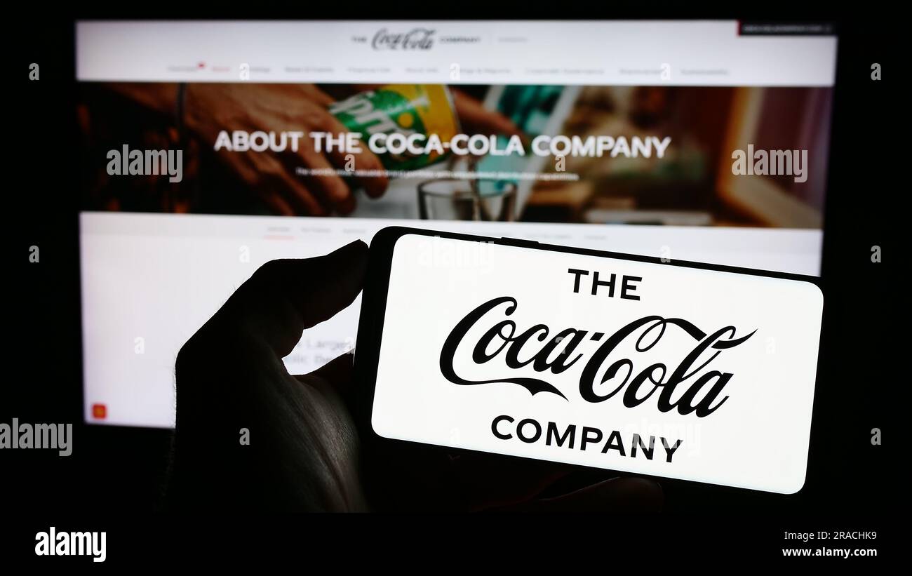 Person holding cellphone with logo of US beverage business The Coca ...