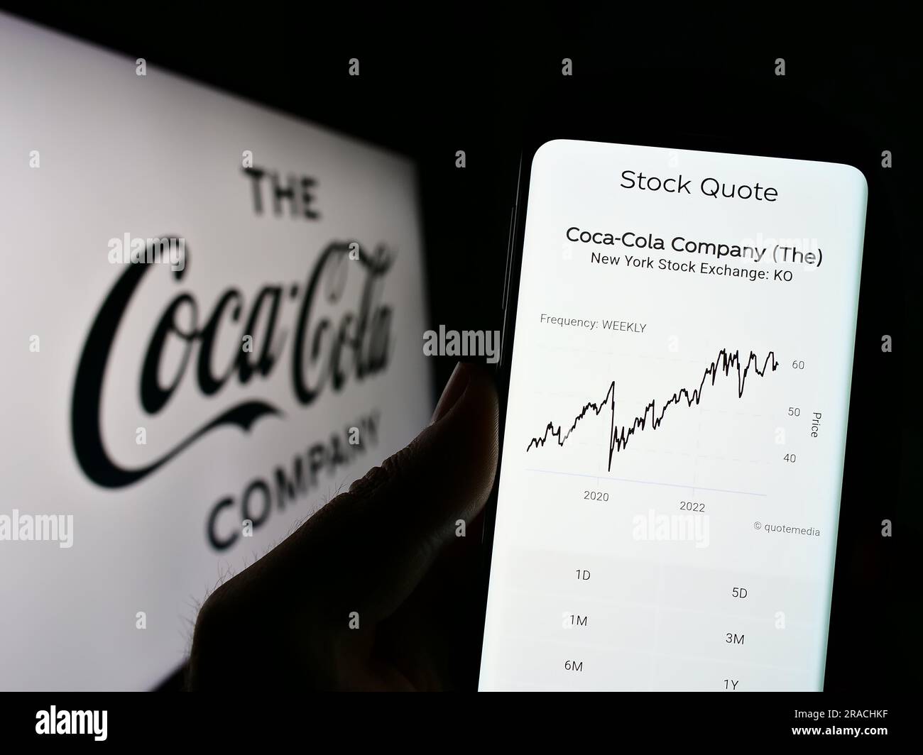 Person holding cellphone with website of US beverage business The Coca ...