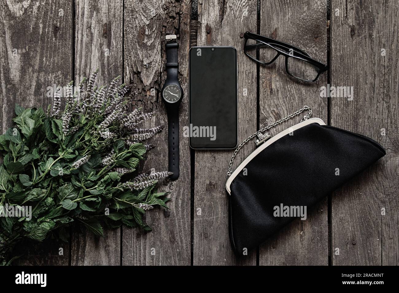 black small bag glasses watch and phone with green screen on an wooden ...