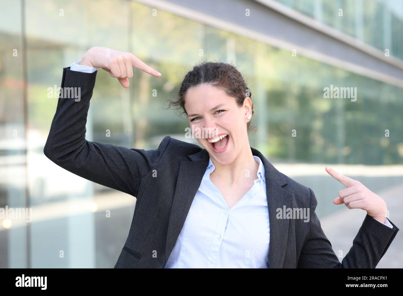 Front view portrait of a proud executive pointing herself in the street ...