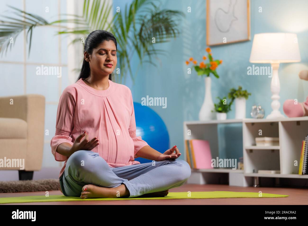 Indian peaceful pregnant woman in lotus pose doing meditation on yoga ...