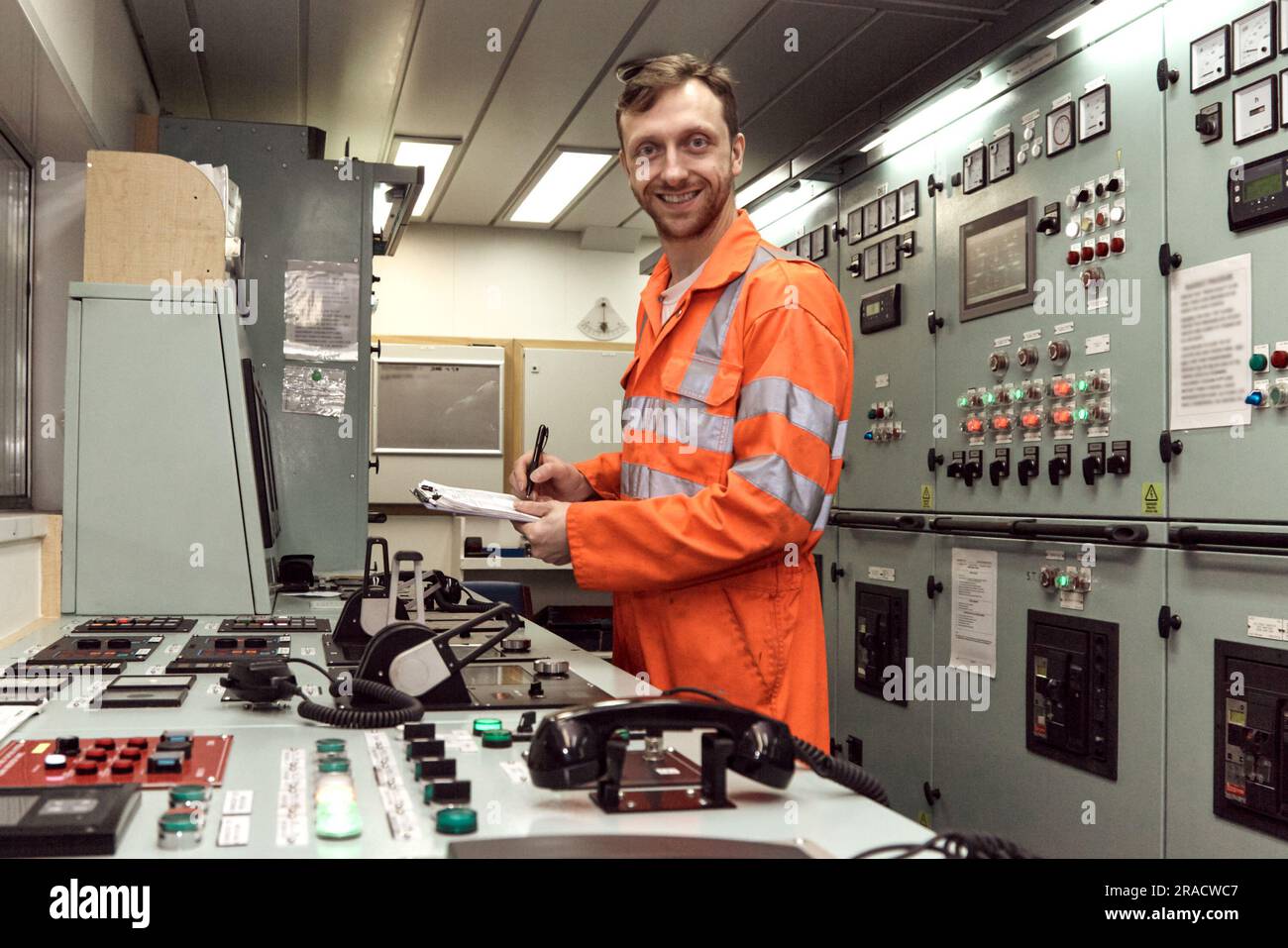 Young offshore marine engineer officer checking equipment in engine ...