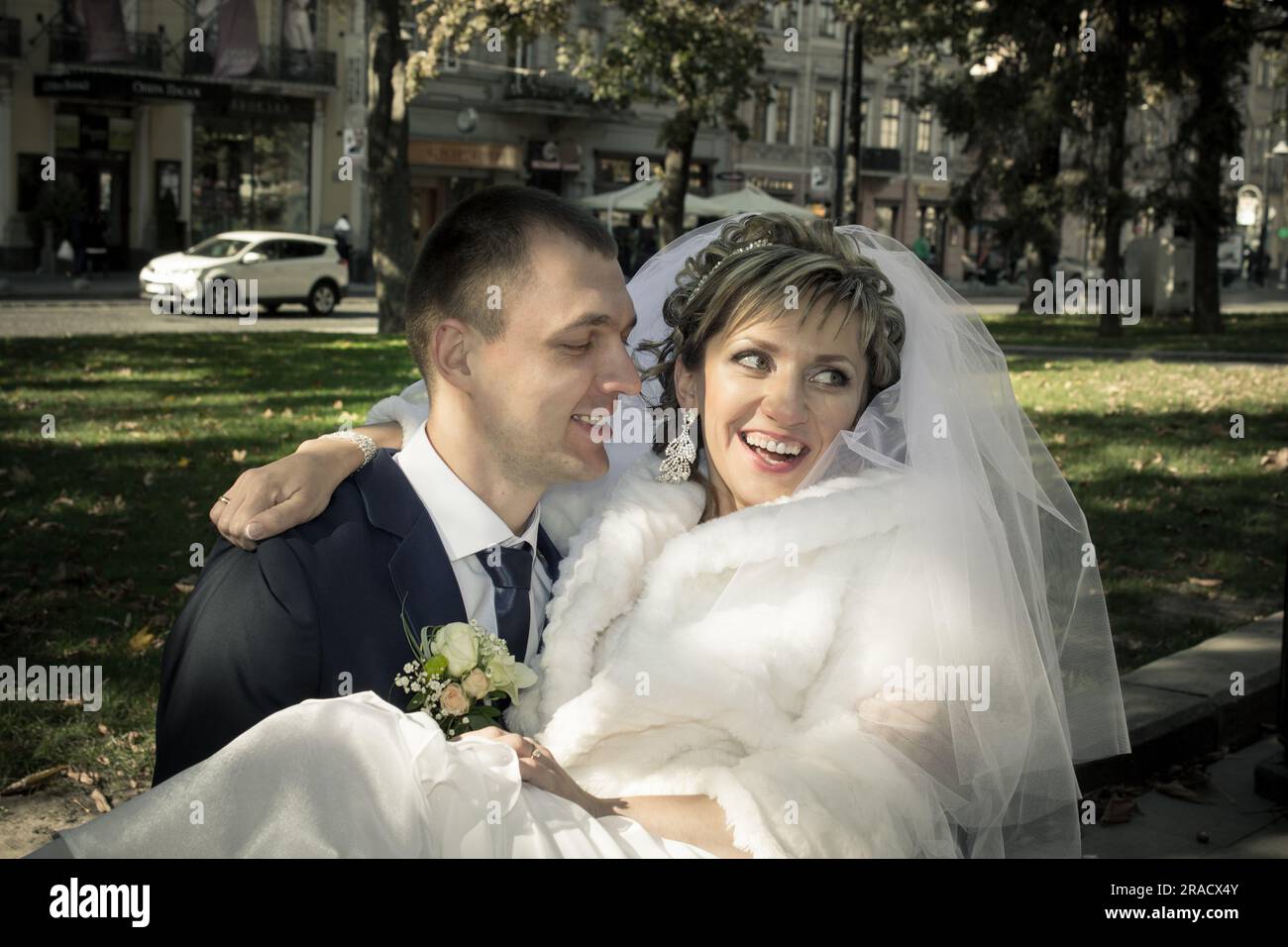 bride sitting on a bench with a smile unscrewing the head of the groom ...