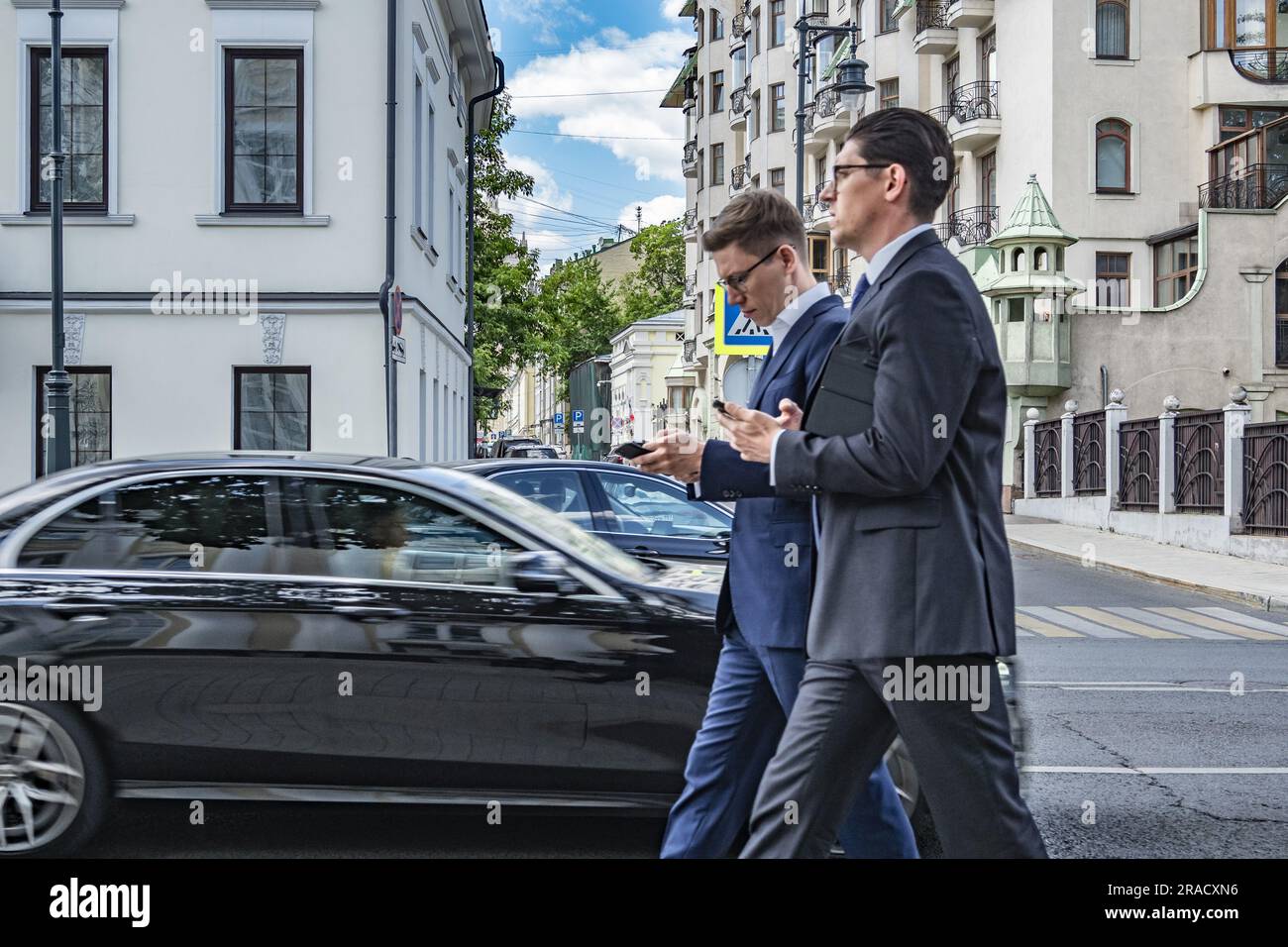 Russia, Moscow. Two men in business suits are walking down the street ...
