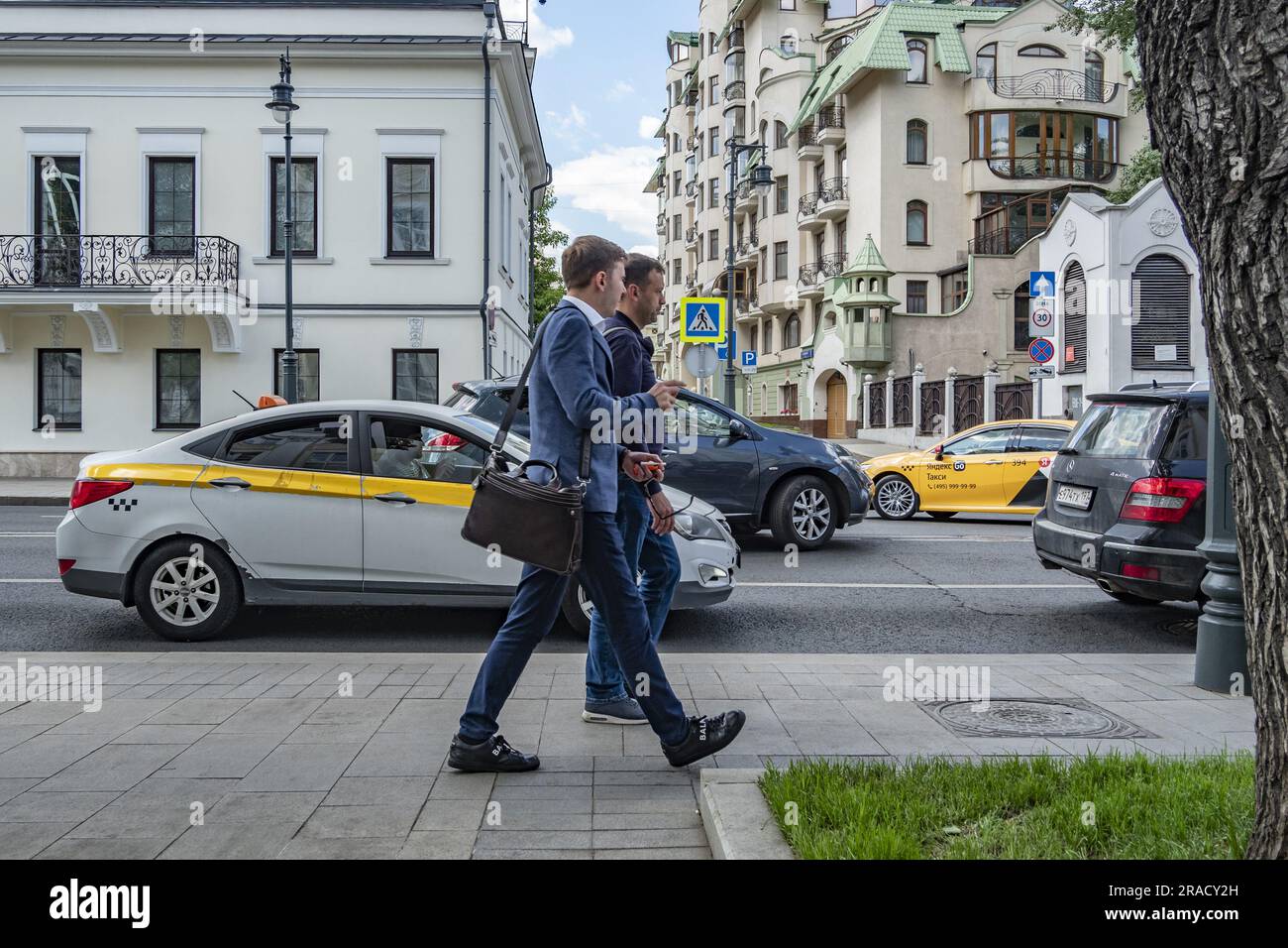 Russia, Moscow. Two men in business suits are walking down the street ...