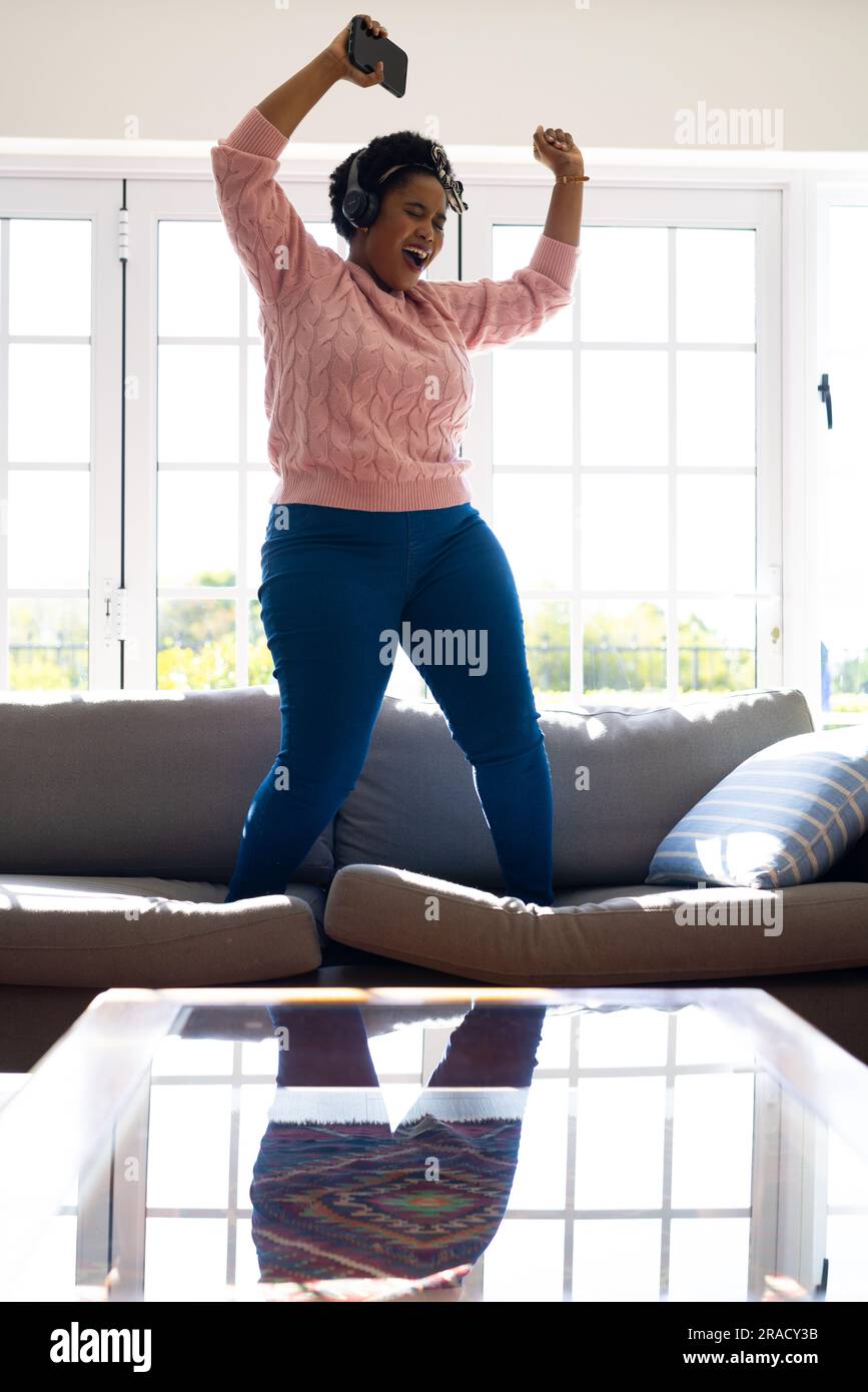 Happy plus size african american woman with headphones and smartphone ...