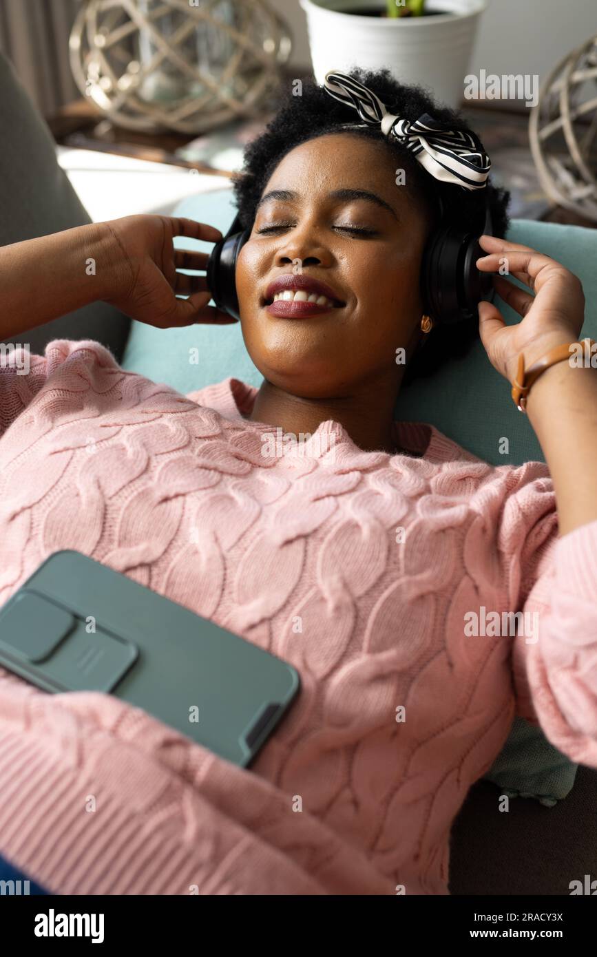 Happy plus size african american woman with headphones and smartphone ...