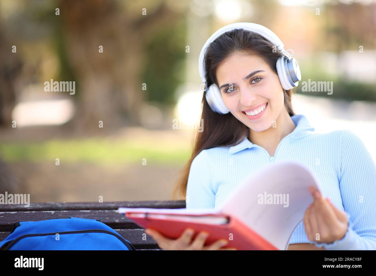 Happy student posing looking at you holding notebook and wearing ...