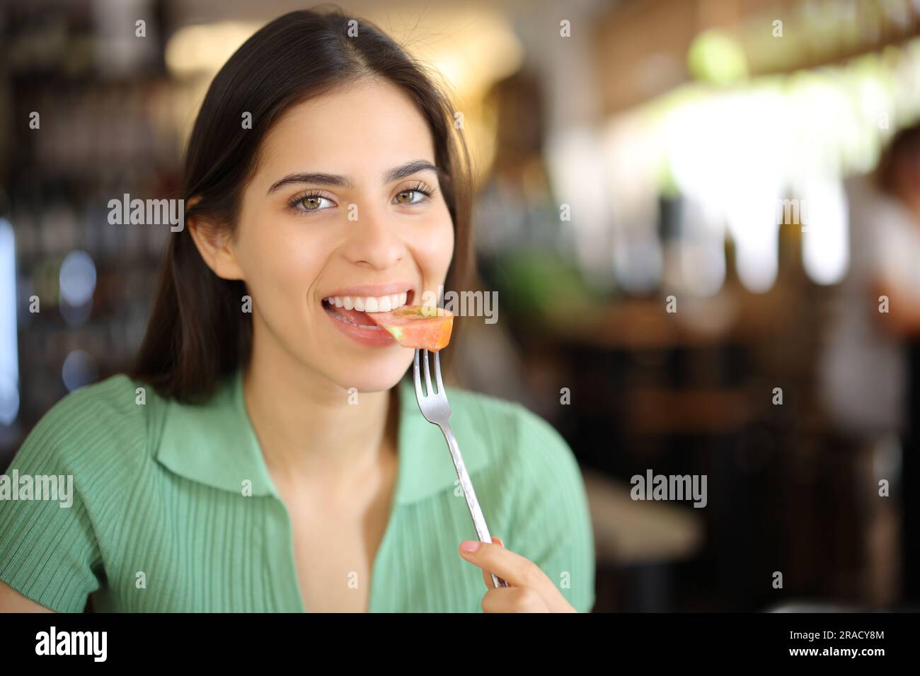 Happy restaurant customer eating tomato looking at camera Stock Photo ...