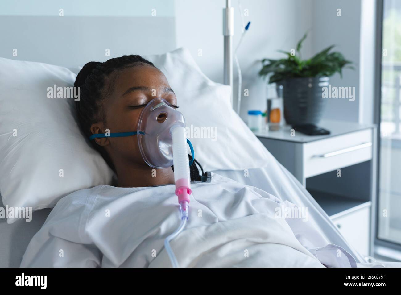 African american female patient with oxygen mask, lying on bed in ...