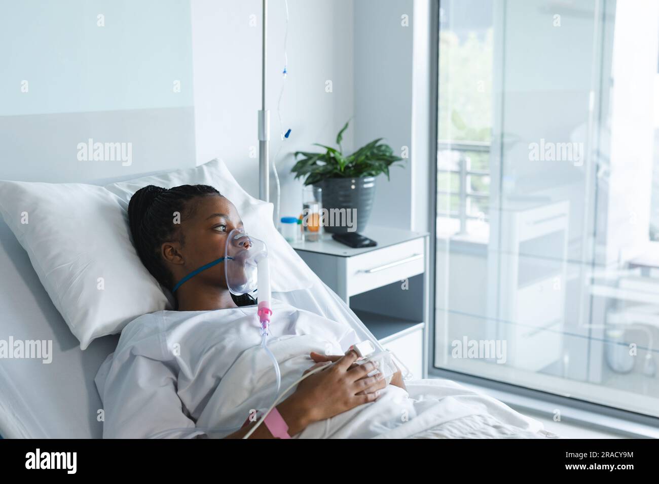 African american female patient with oxygen mask, lying on bed in ...