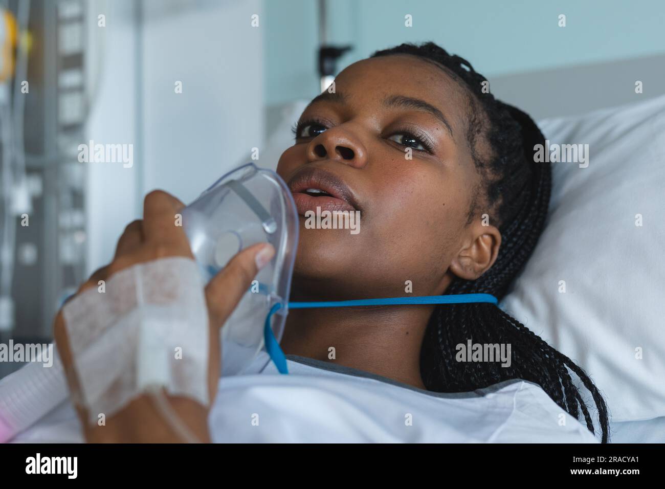 African american female patient with oxygen mask, lying on bed in ...