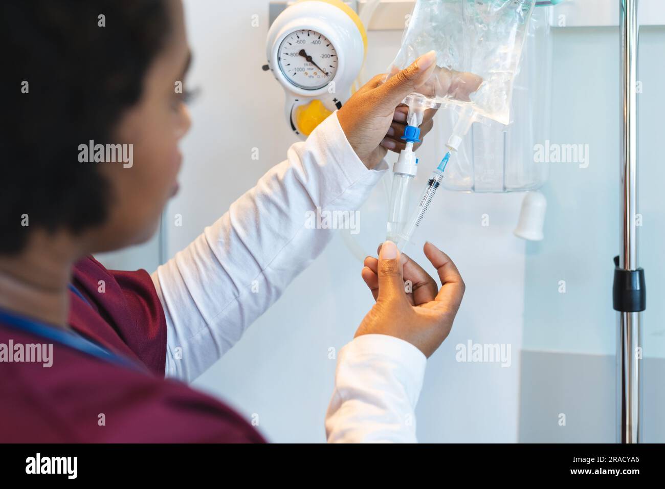 African american female doctor wearing scrubs, applying drip in ...