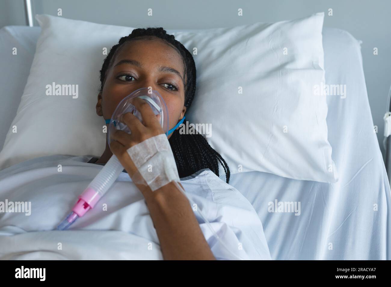 African american female patient with oxygen mask, lying on bed in ...