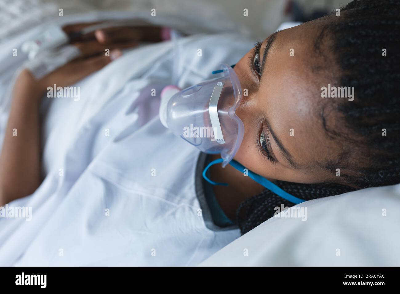 African american female patient with oxygen mask, lying on bed in ...