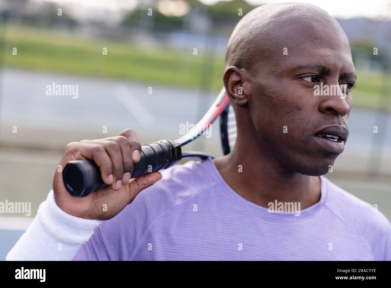Serious african american male tennis player holding tennis racket on ...