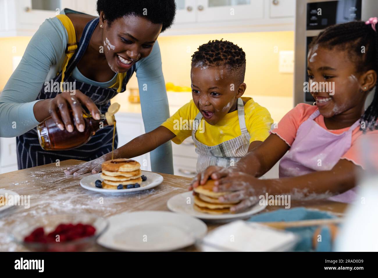 Happy african american mother pouring honey on pancakes served for ...