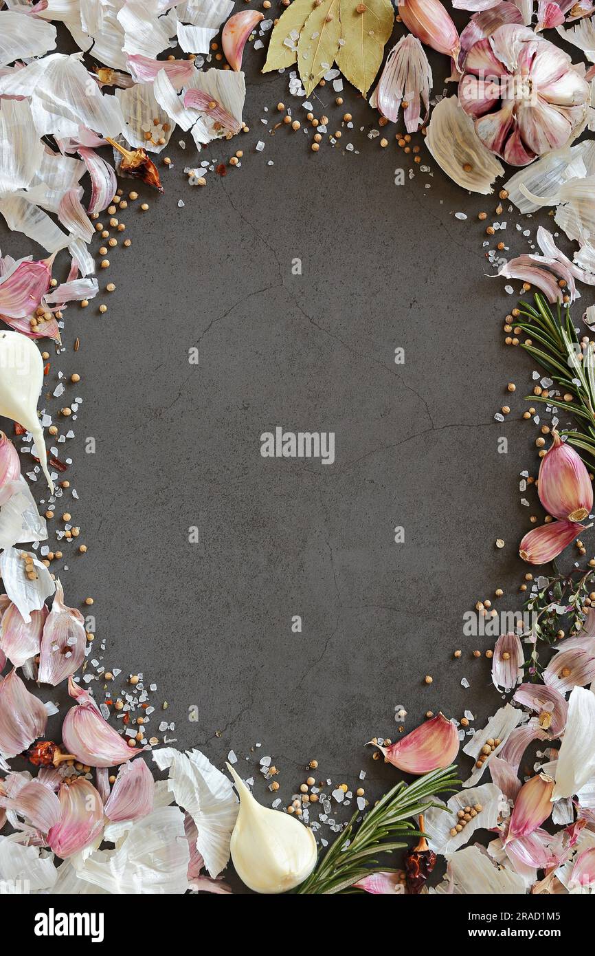 Garlic, garlic skins, herbs and spices creating an oval picture border ...