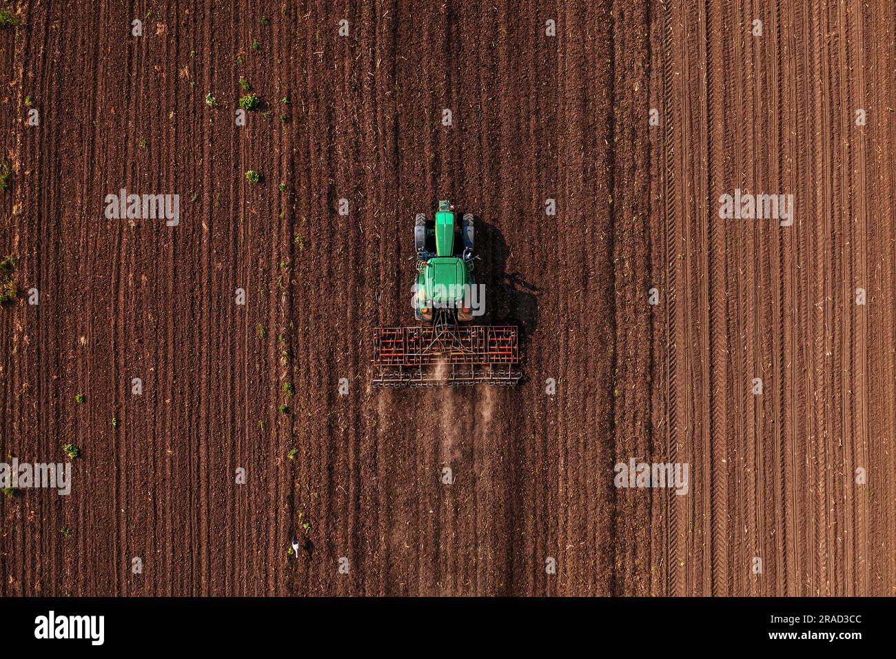 Green tractor vehicle with tiller attached performing field tillage ...