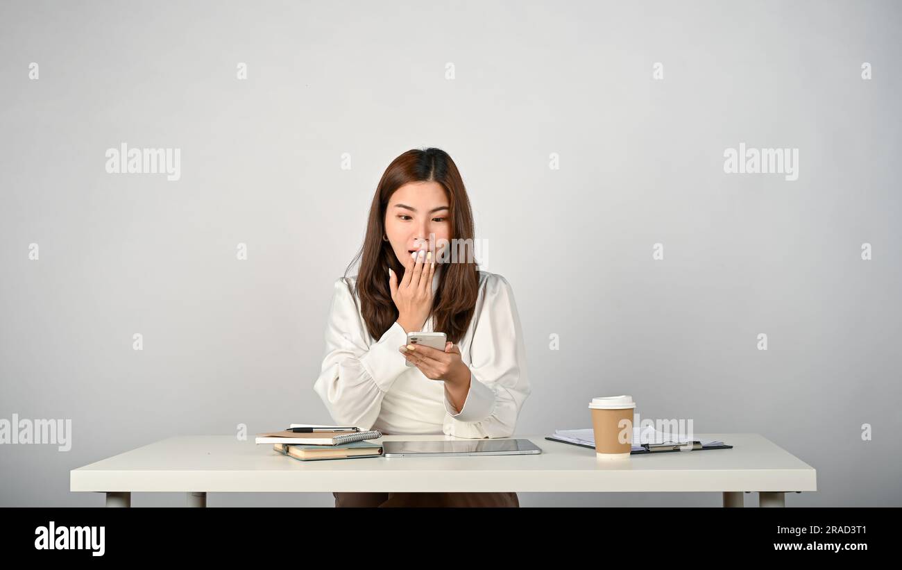 A shocked and stunned young Asian businesswoman covering her mouth ...