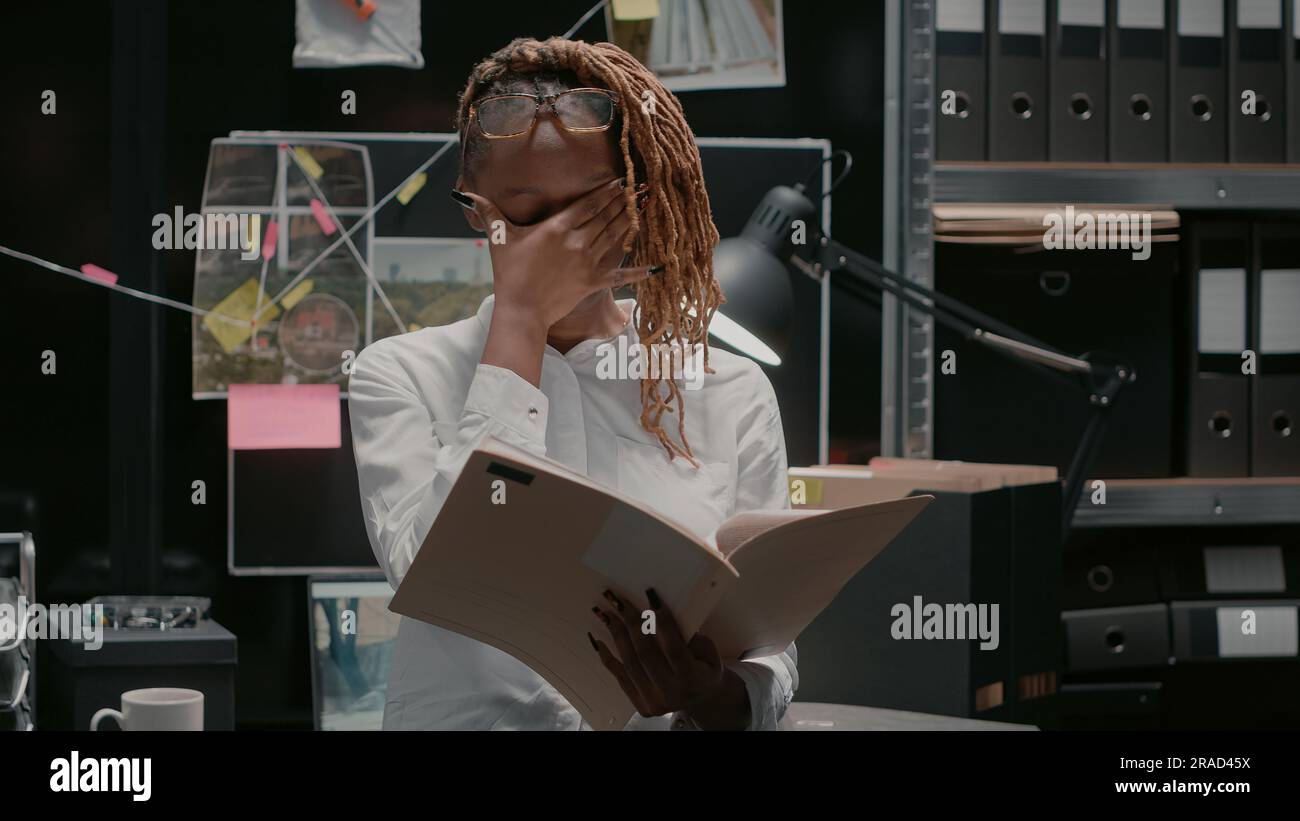 Law officer studying clues on case files in police archive office ...