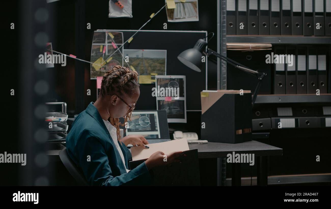 Private officer looking at criminal records in incident room, examining ...