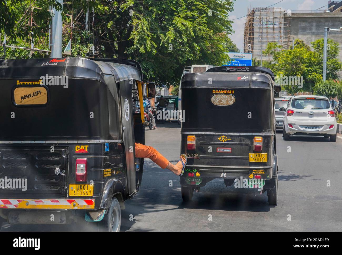The driver of an auto rickshaw, left, pushes using his foot as he ...
