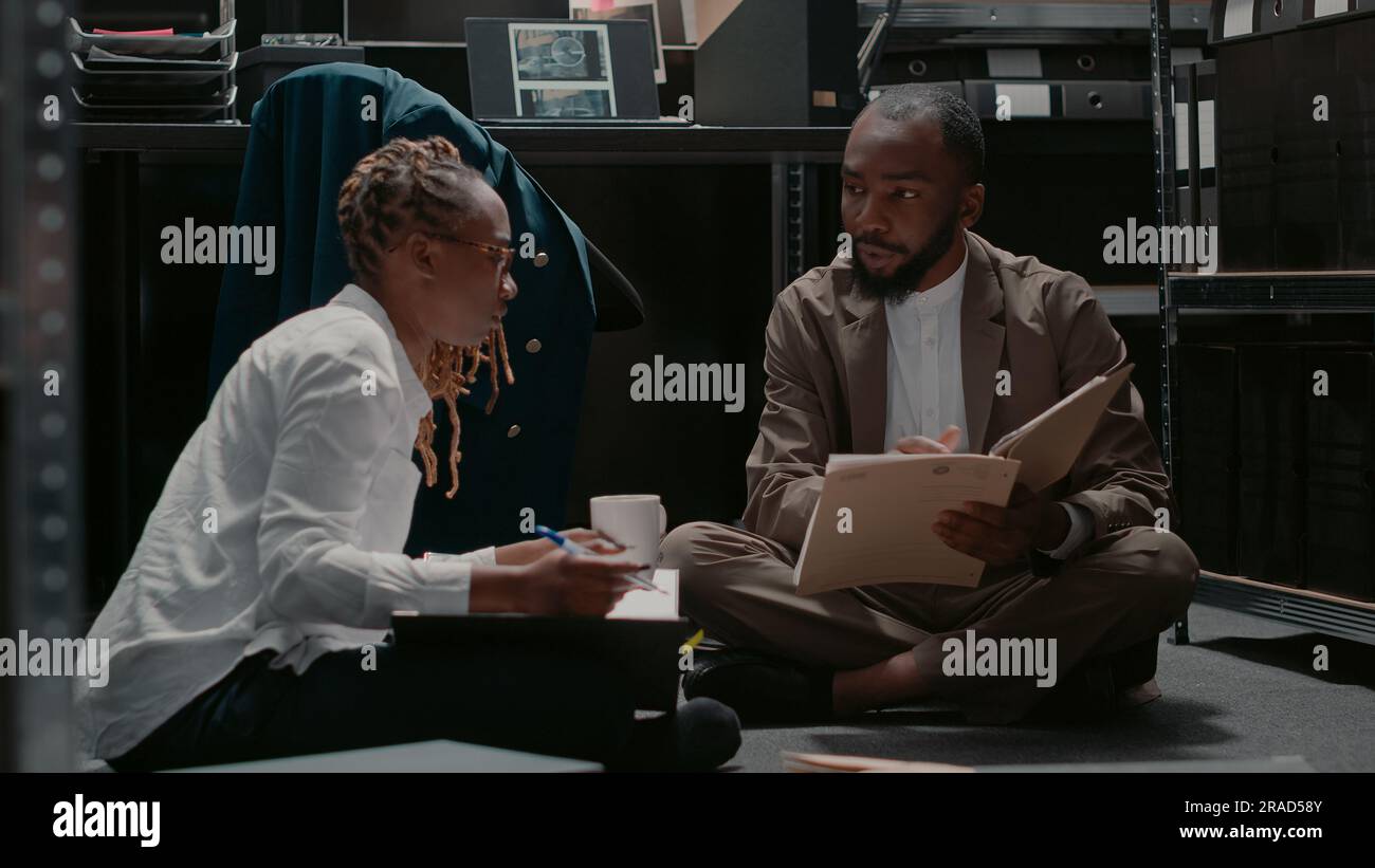 Two private investigators examining clues and case files, sitting on ...