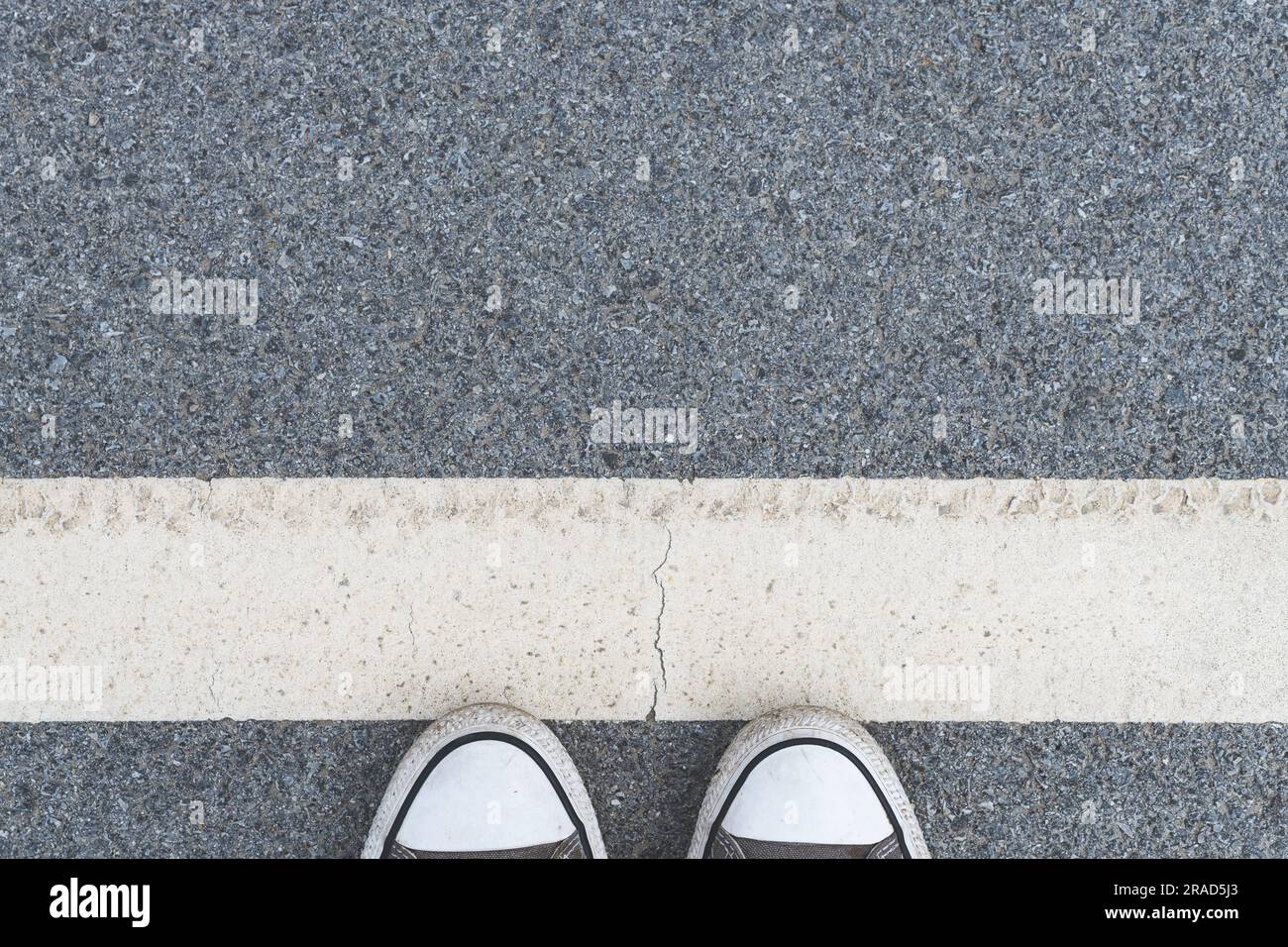 Stylish sneakers on asphalt road at white line as a border, top view ...