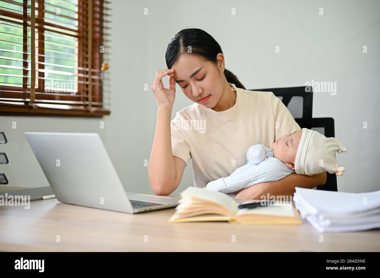 Young stressful mother working from home and raising baby at the same ...