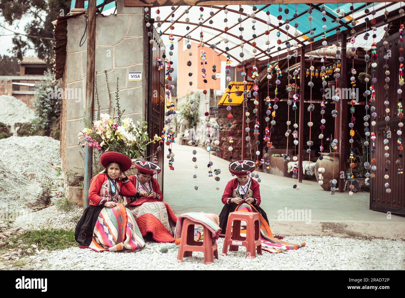 local woman in colourful traditional clothes weave on street by market ...
