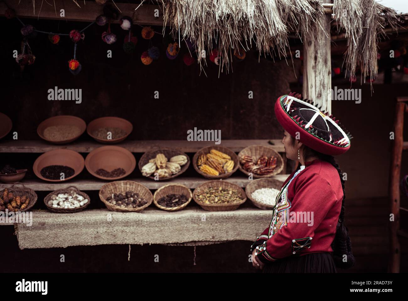 local woman in traditional clothes stands with baskets of local food ...