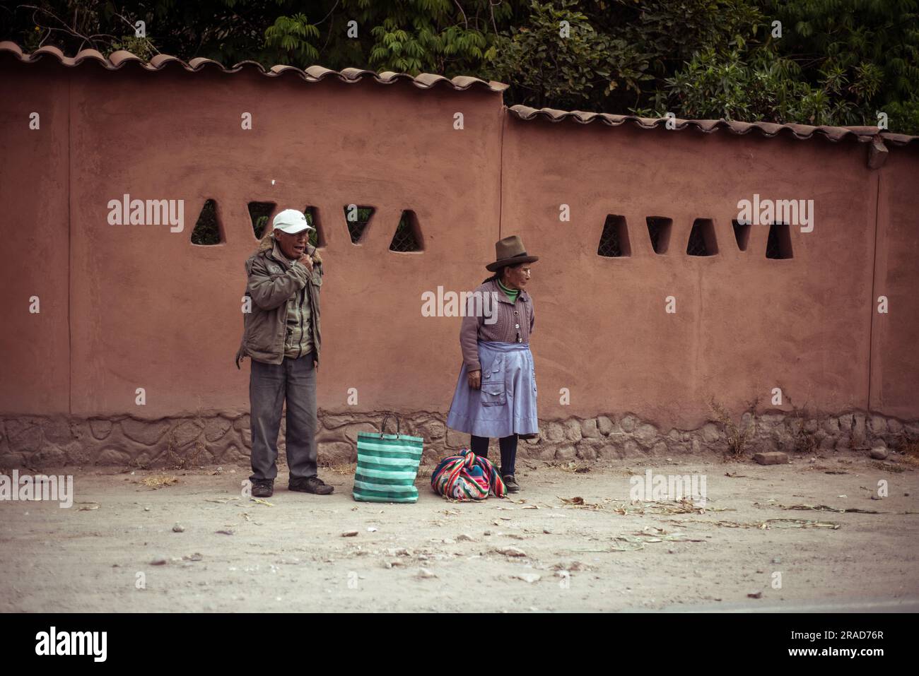 Native Peruvians stand in front of mud wall waiting for bus Stock Photo ...