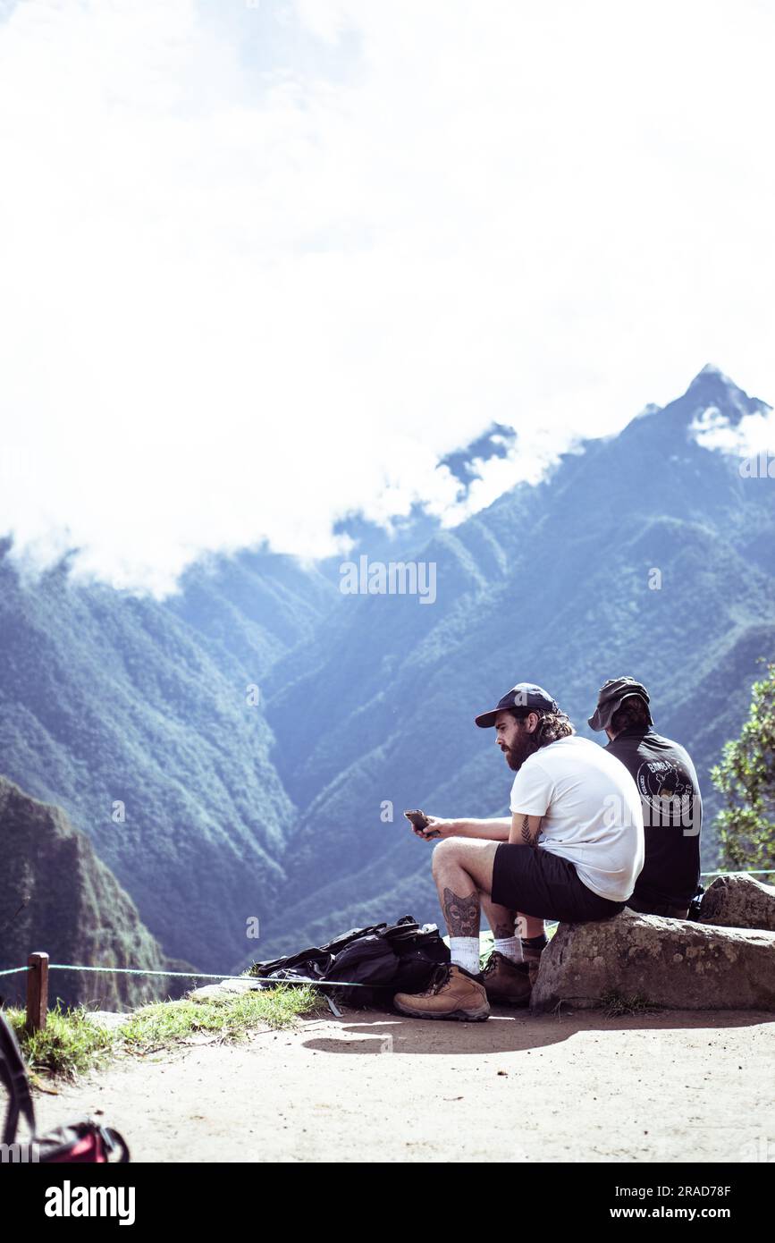 Two traveller men sit and rest at top of Machu Picchu ruins Stock Photo ...