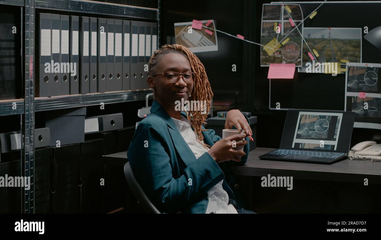 Young policewoman working in incident room, sitting in police archive ...