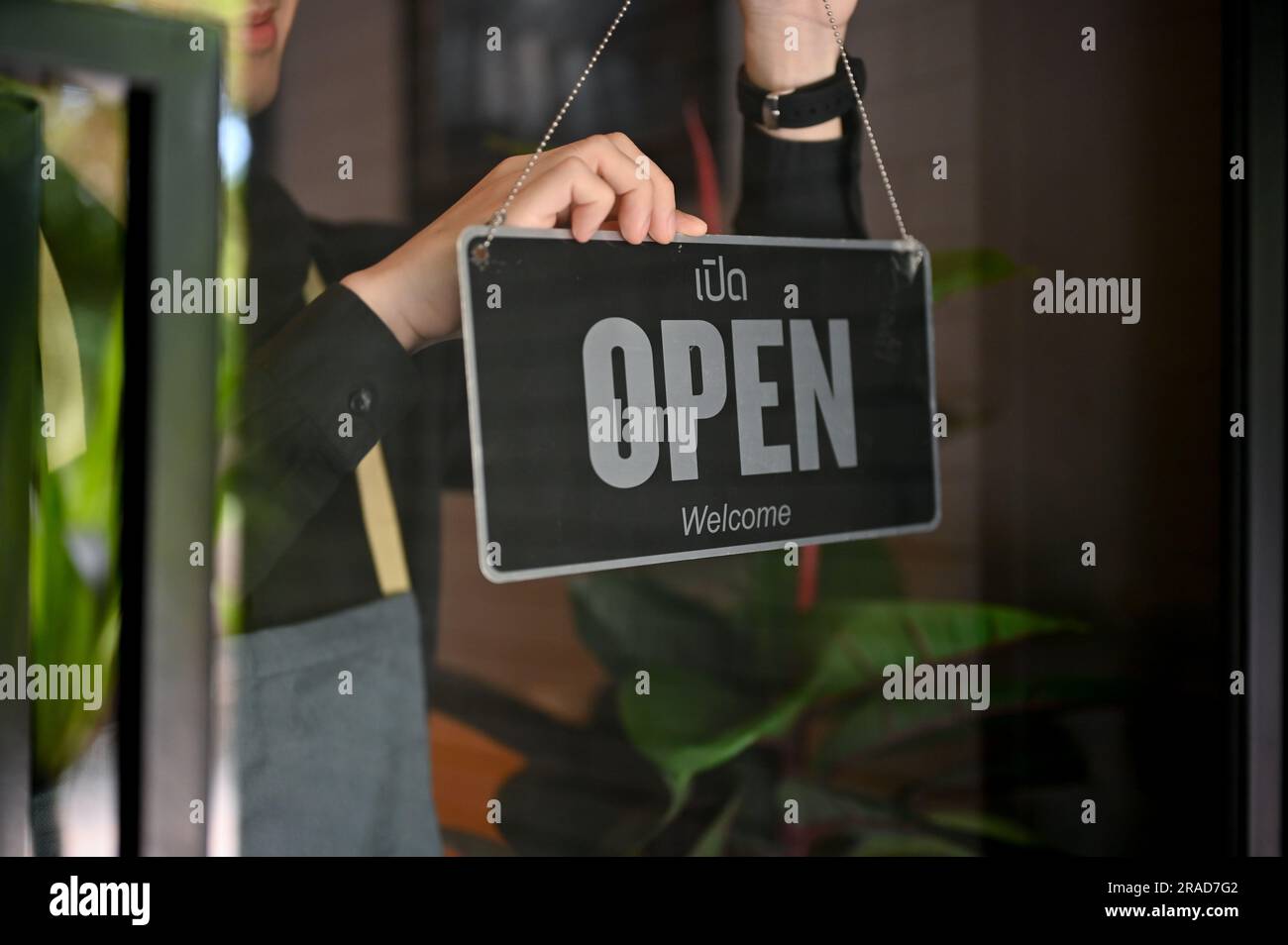 Young Asian coffee shop owner opening his shop, turning the open sign ...