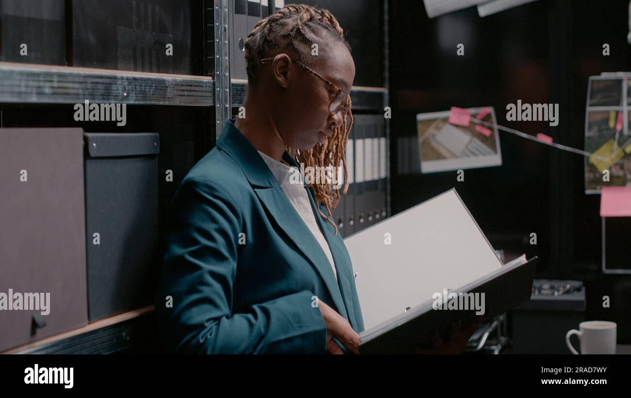 Police investigator reading case file in evidence room filled with ...