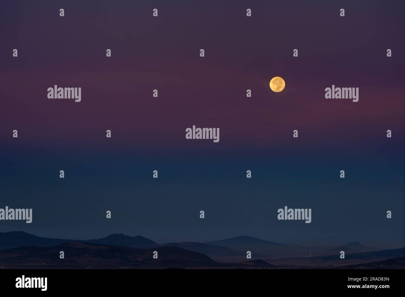 Full moon just before hiding on the horizon with a purple sky Stock ...
