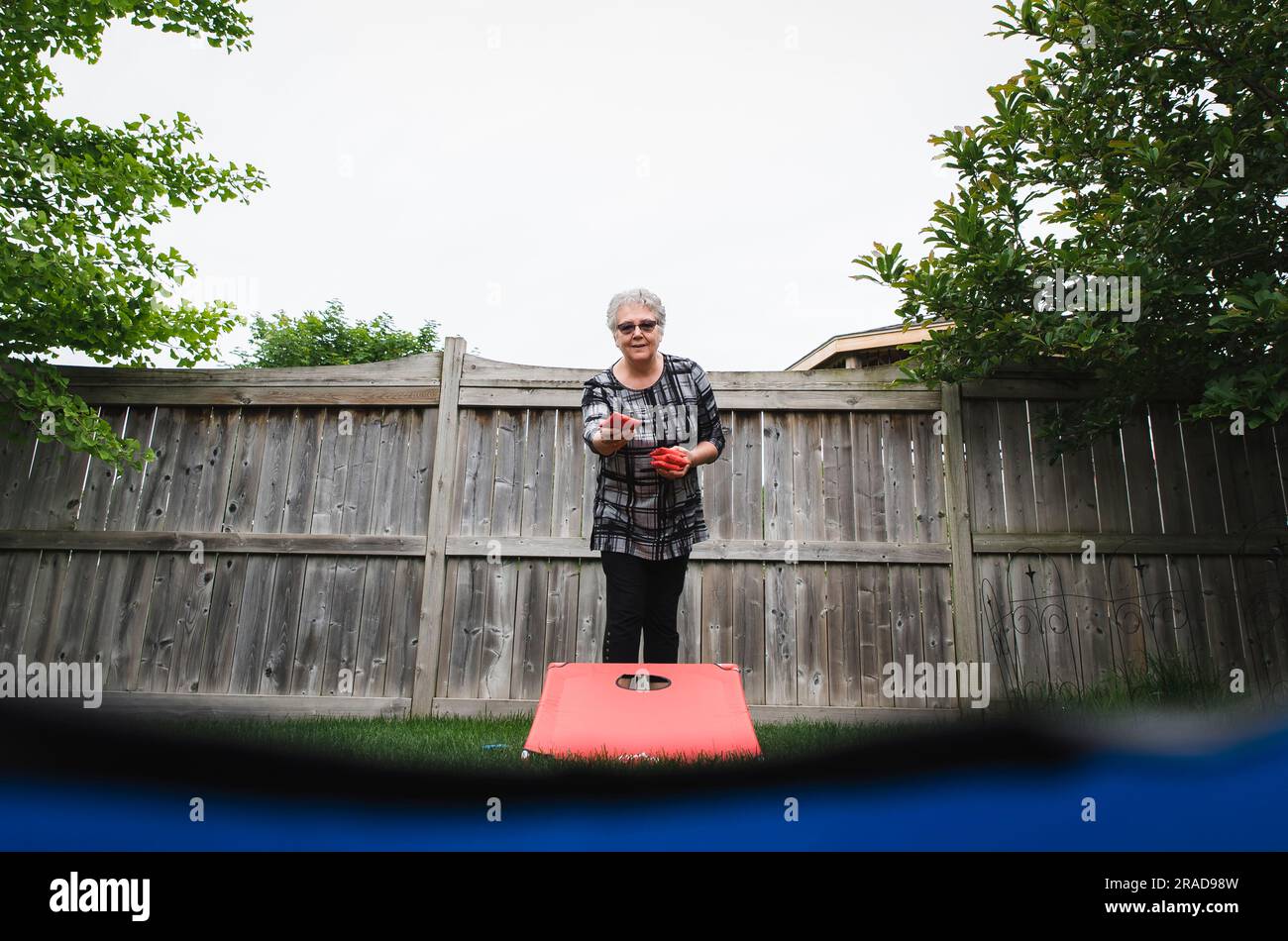 Mature woman throwing bean bag during corn hole game shot from below ...