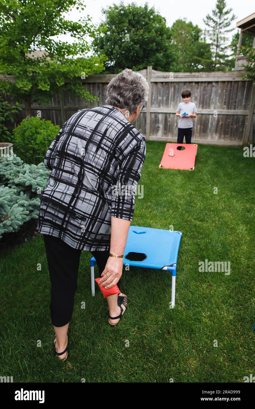 Grandmother playing corn hole game with grandson in the backyard Stock ...