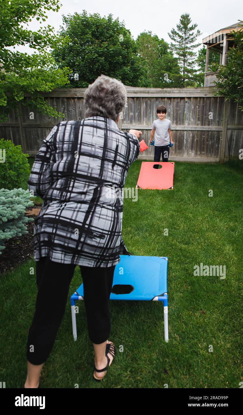 Grandmother playing corn hole game with grandson in the backyard Stock ...