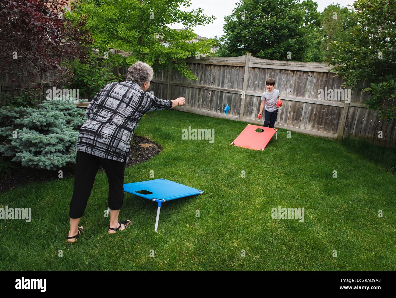 Grandmother and grandson playing corn hole game in a backyard Stock ...