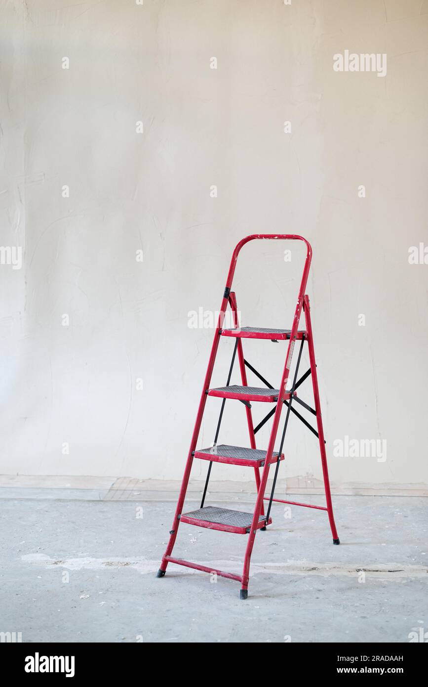 Red ladder against concrete wall of room interior under construction ...
