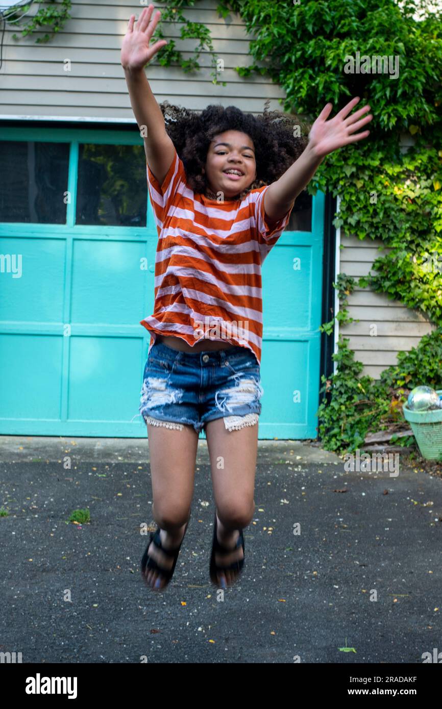Tween girl in backyard jumping Stock Photo - Alamy